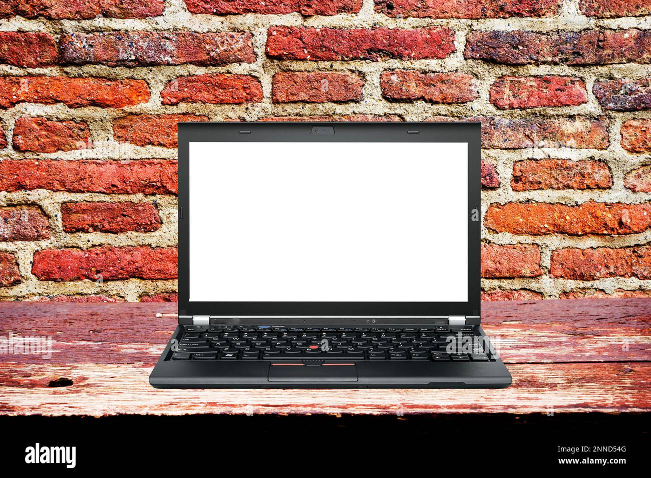 Blank screen laptop on wooden shelves with blurred brick wall ...
