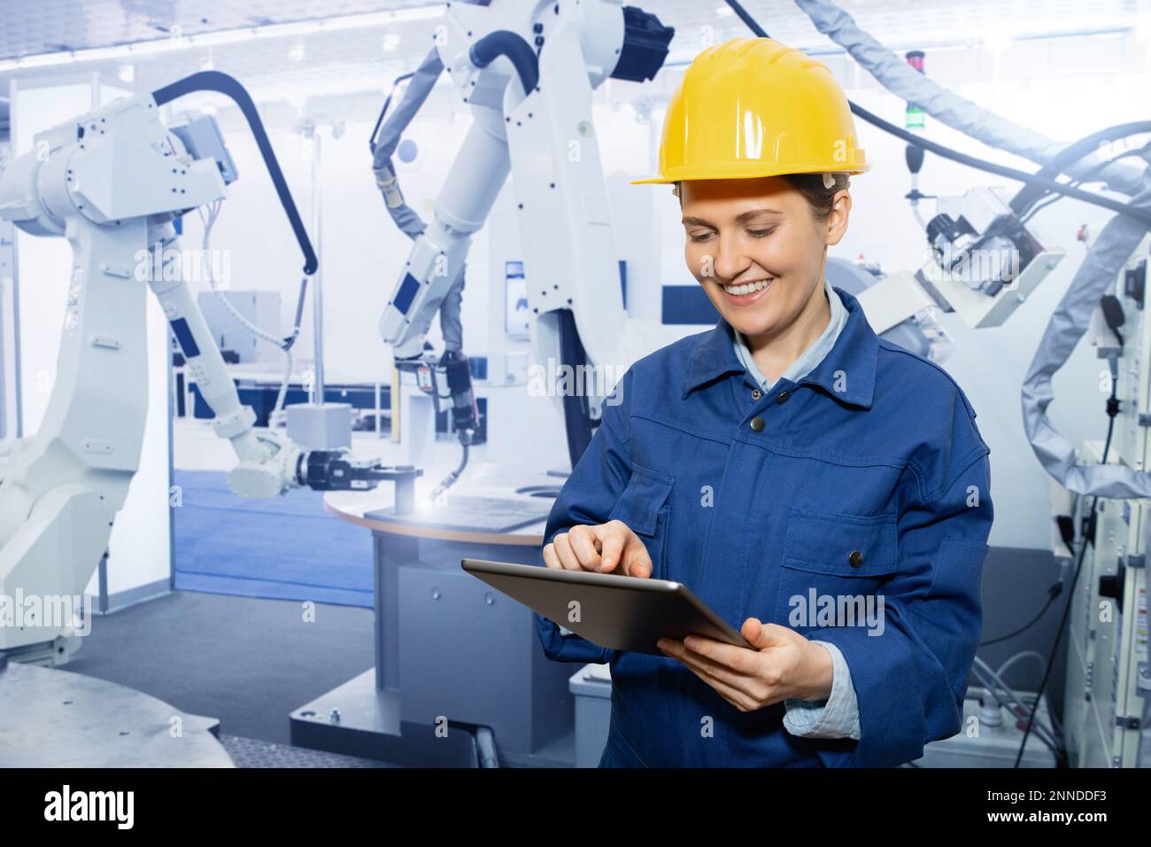 Woman engineer uses a digital tablet to control robots in a smart ...