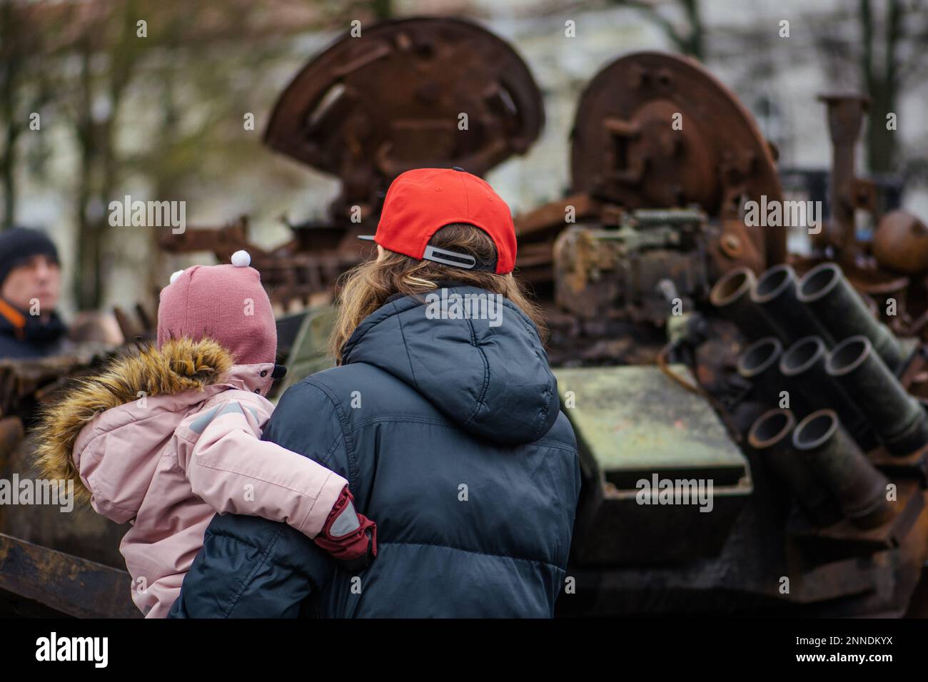 Father with daughter near a burnt and melted rusty wreckage of a Soviet ...