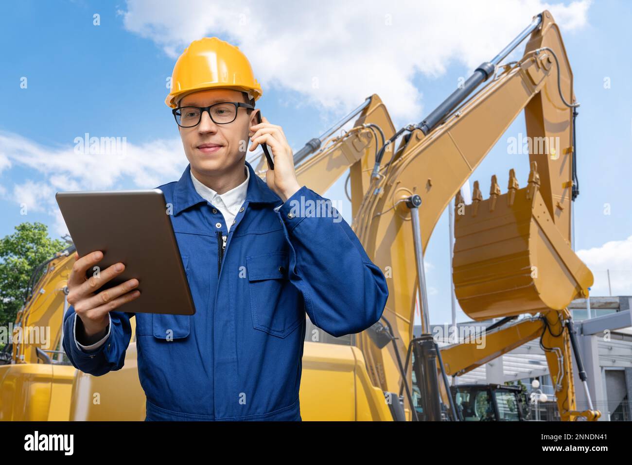 Engineer in a helmet with a digital tablet and phone on the background ...