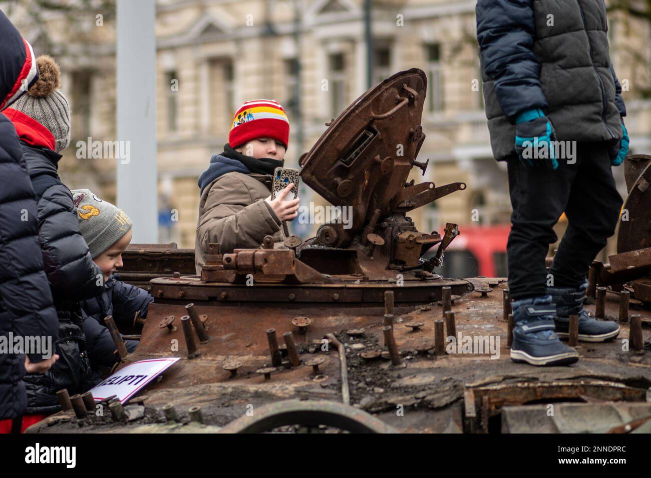 Children playing on a burnt and melted rusty wreckage of a Soviet ...