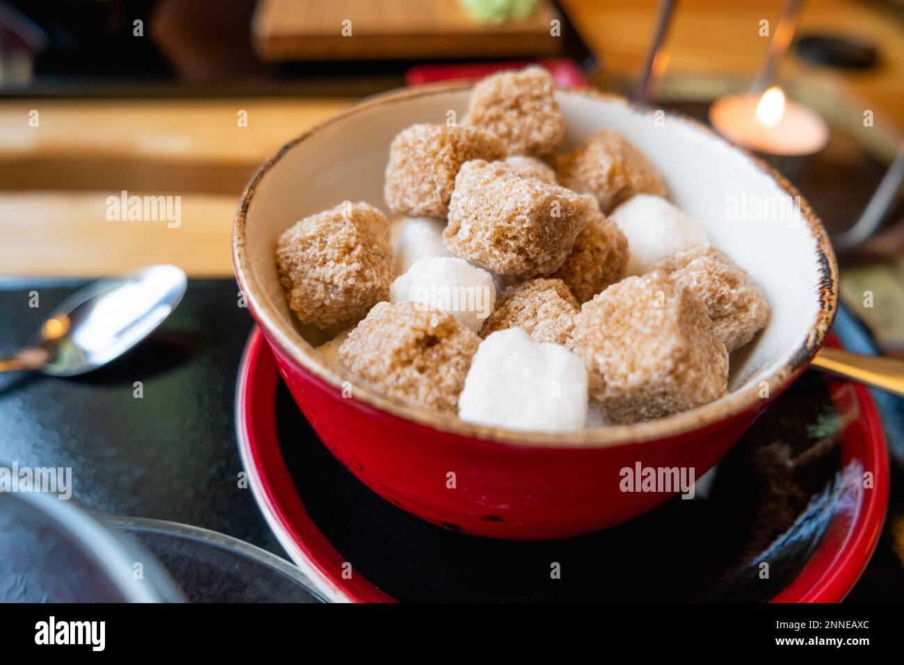 Red bowl with two types of sugar - white and cane sugar. Sweet cubes ...