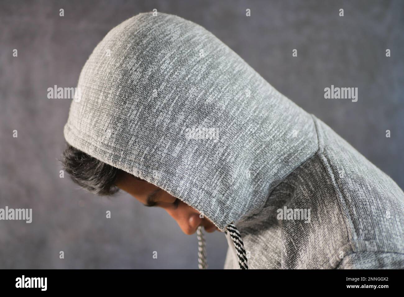 sad man in hood cover face with hands isolated in black Stock Photo - Alamy