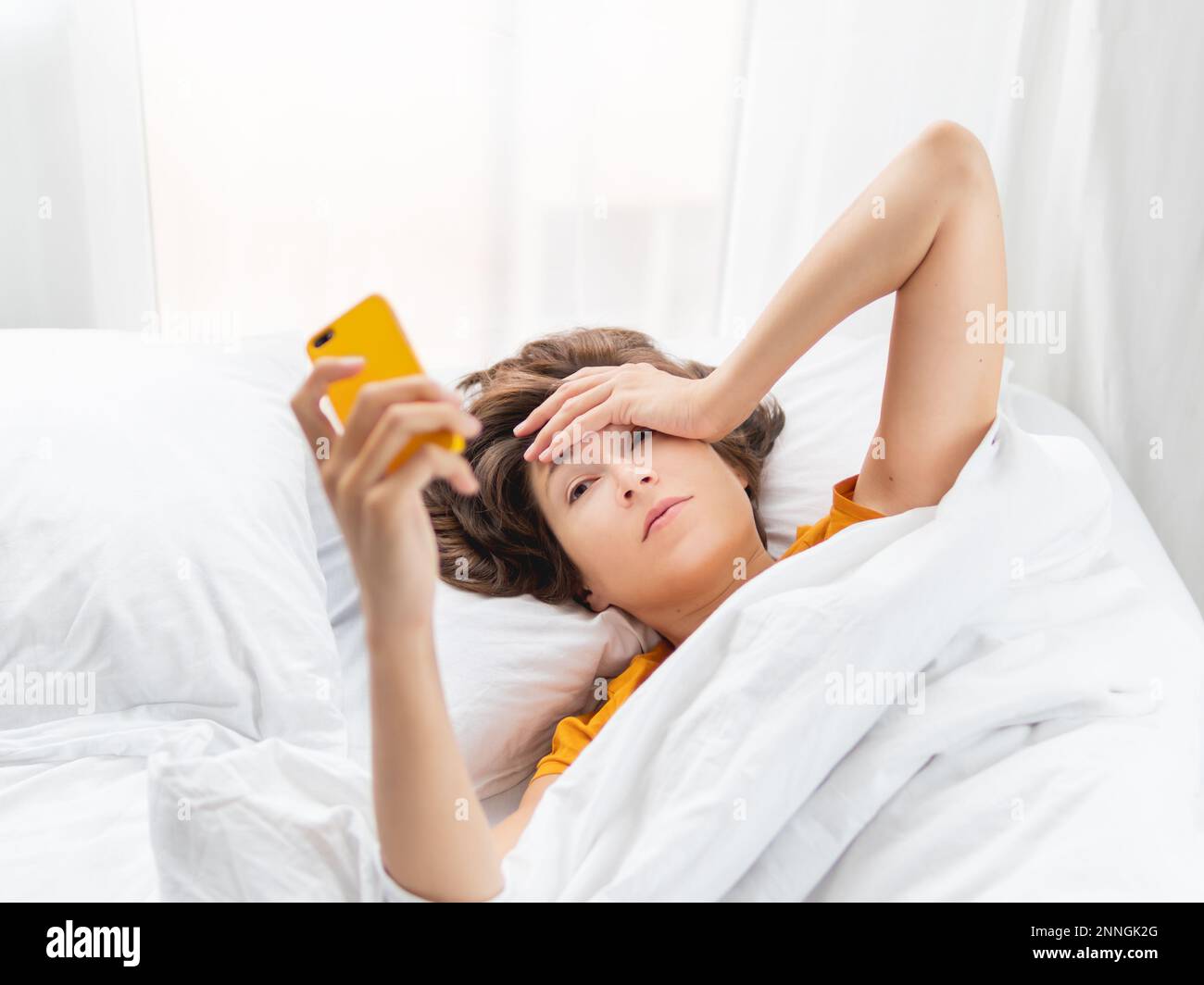 Sleepy woman looks on smartphone screen. Checking e-mail box right ...