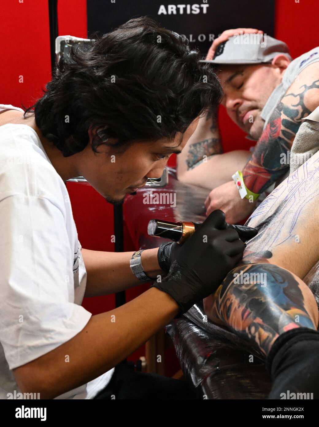 Brighton UK. 25th February 2023. Tattoo artist Amir Lamer works on ...