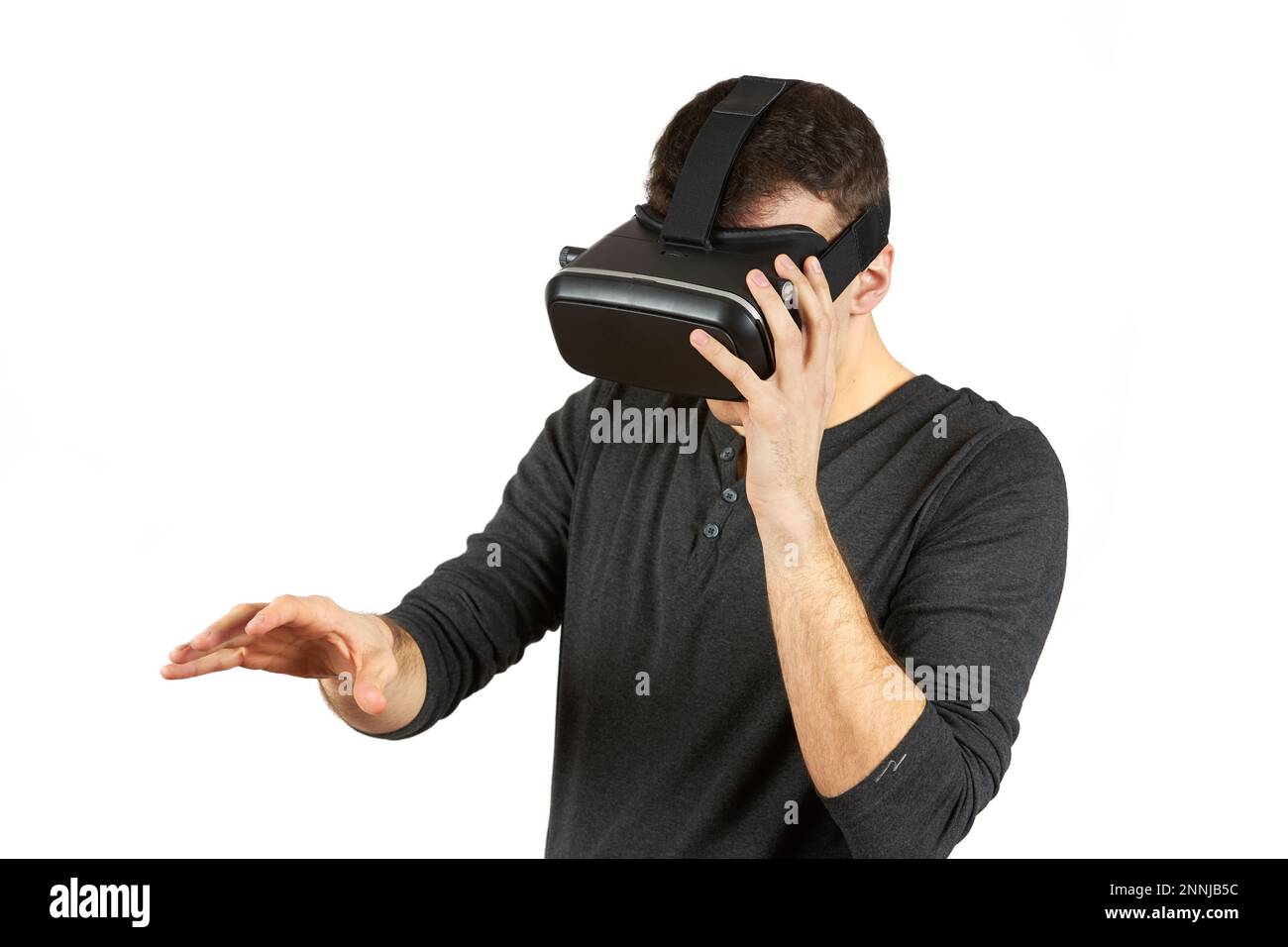 A young man with a virtual reality helmet on his head pulls his hand ...