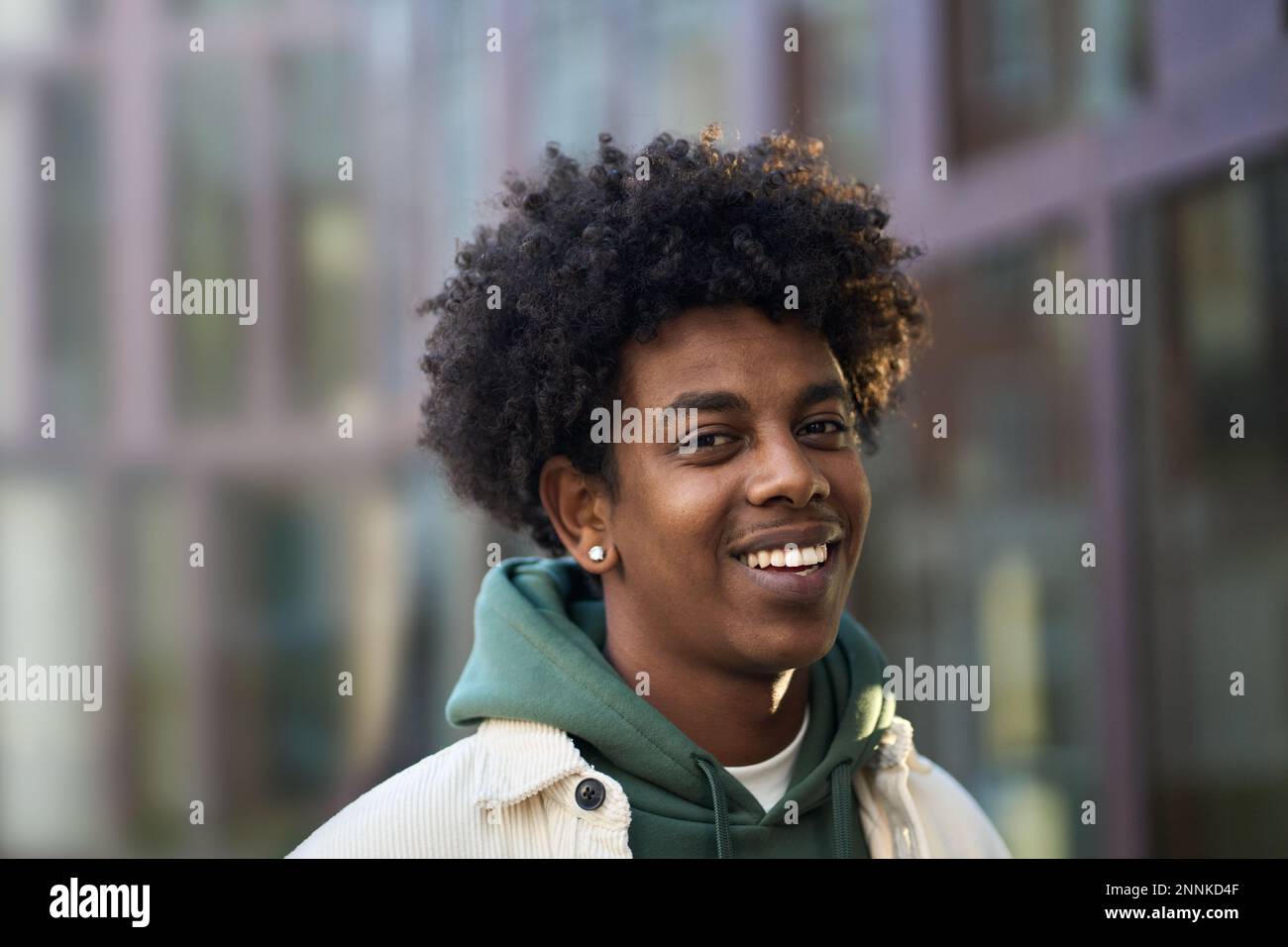 Smiling young gen z African American teen standing at city street ...