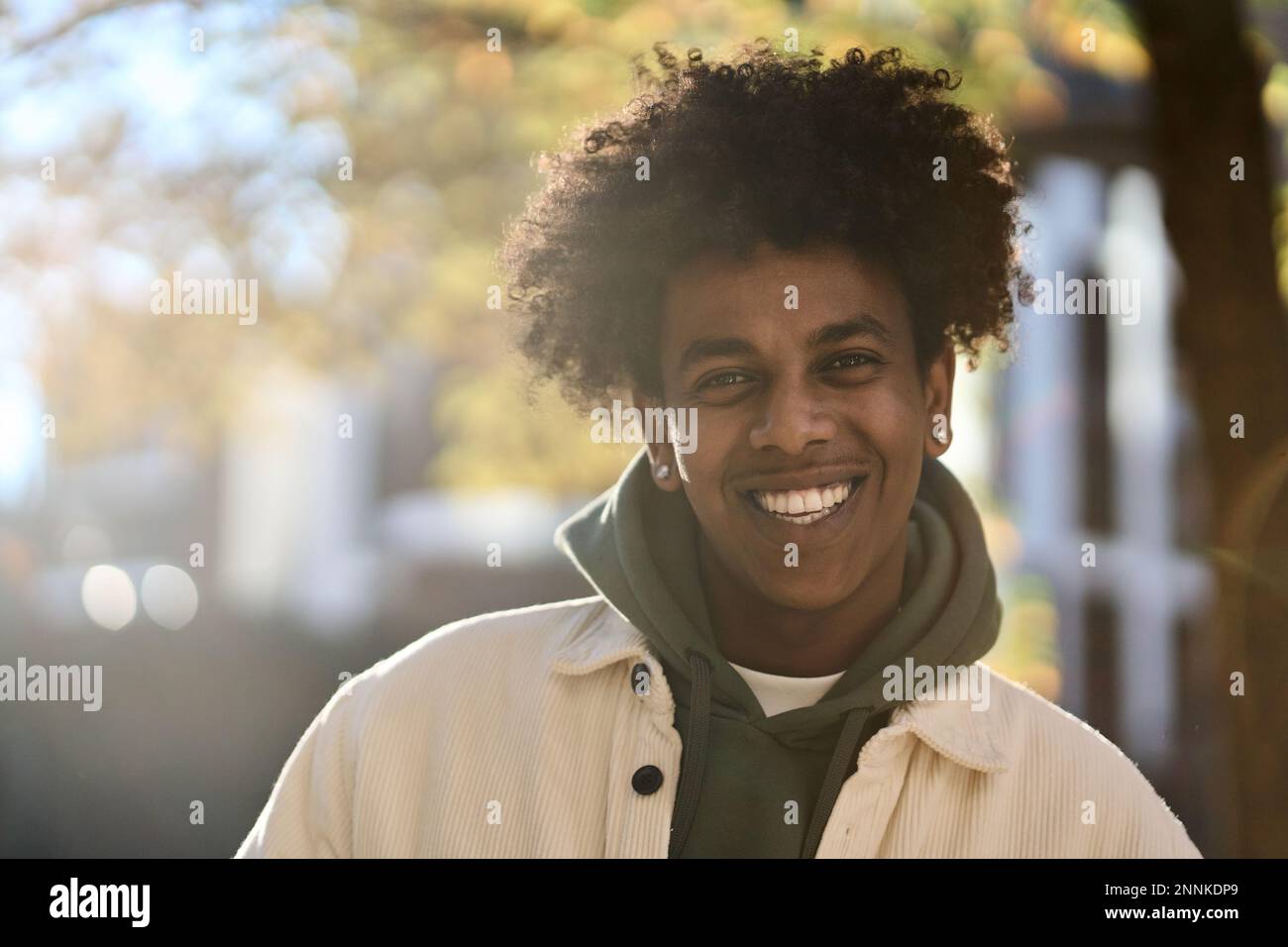 Happy young gen z African American teen standing at sunny city park ...
