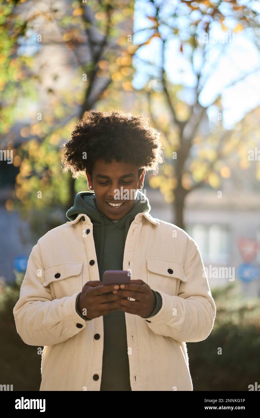 Generation z happy African American guy using mobile phone outdoors ...