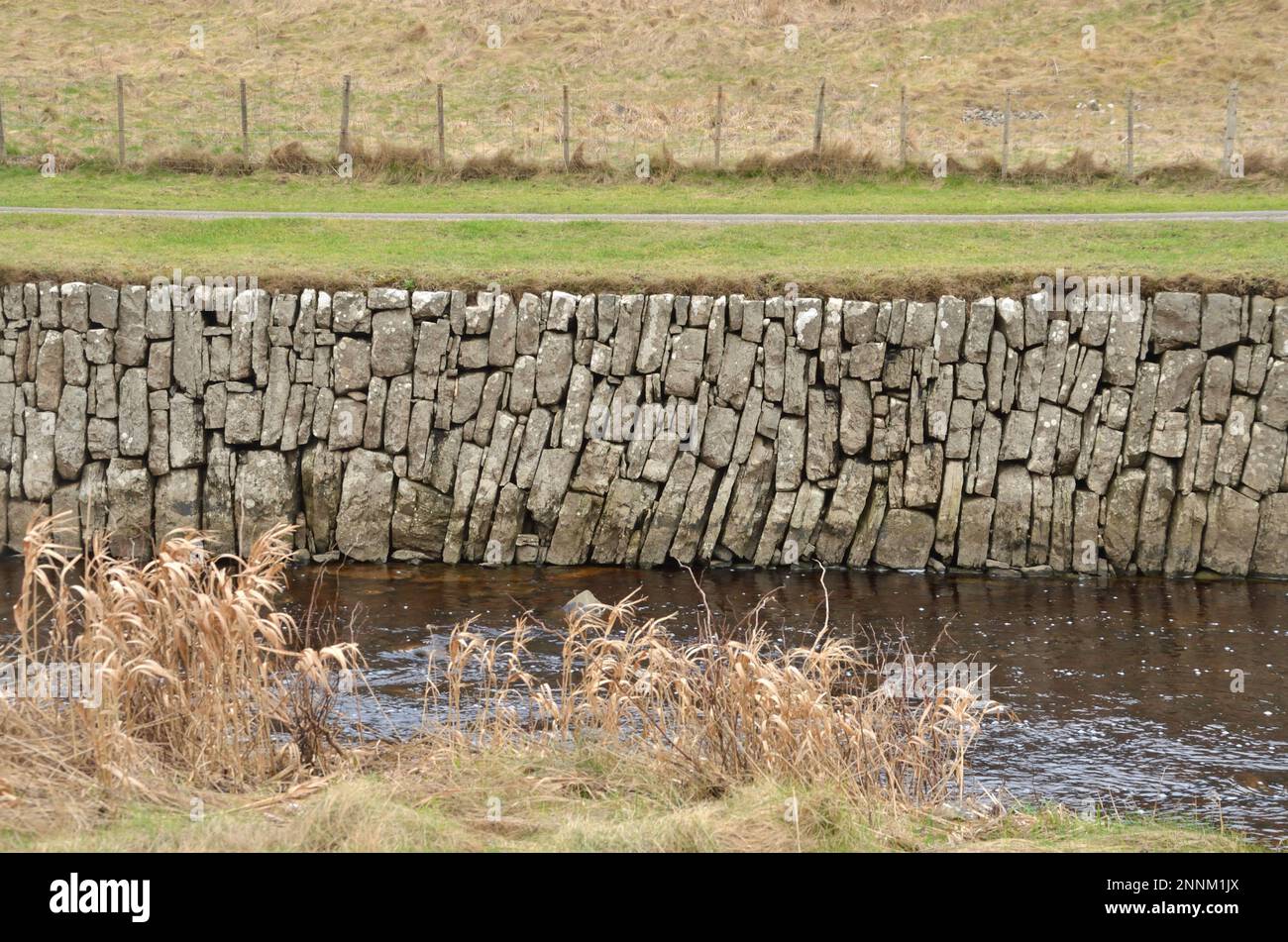 A riverside retaining wall with unusual vertically coursed natural ...