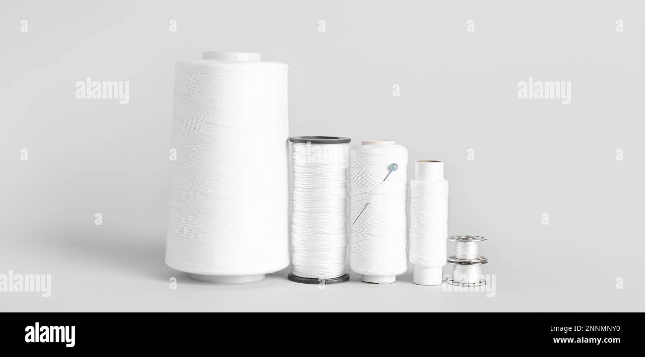 White threads with sewing pin on light background Stock Photo - Alamy