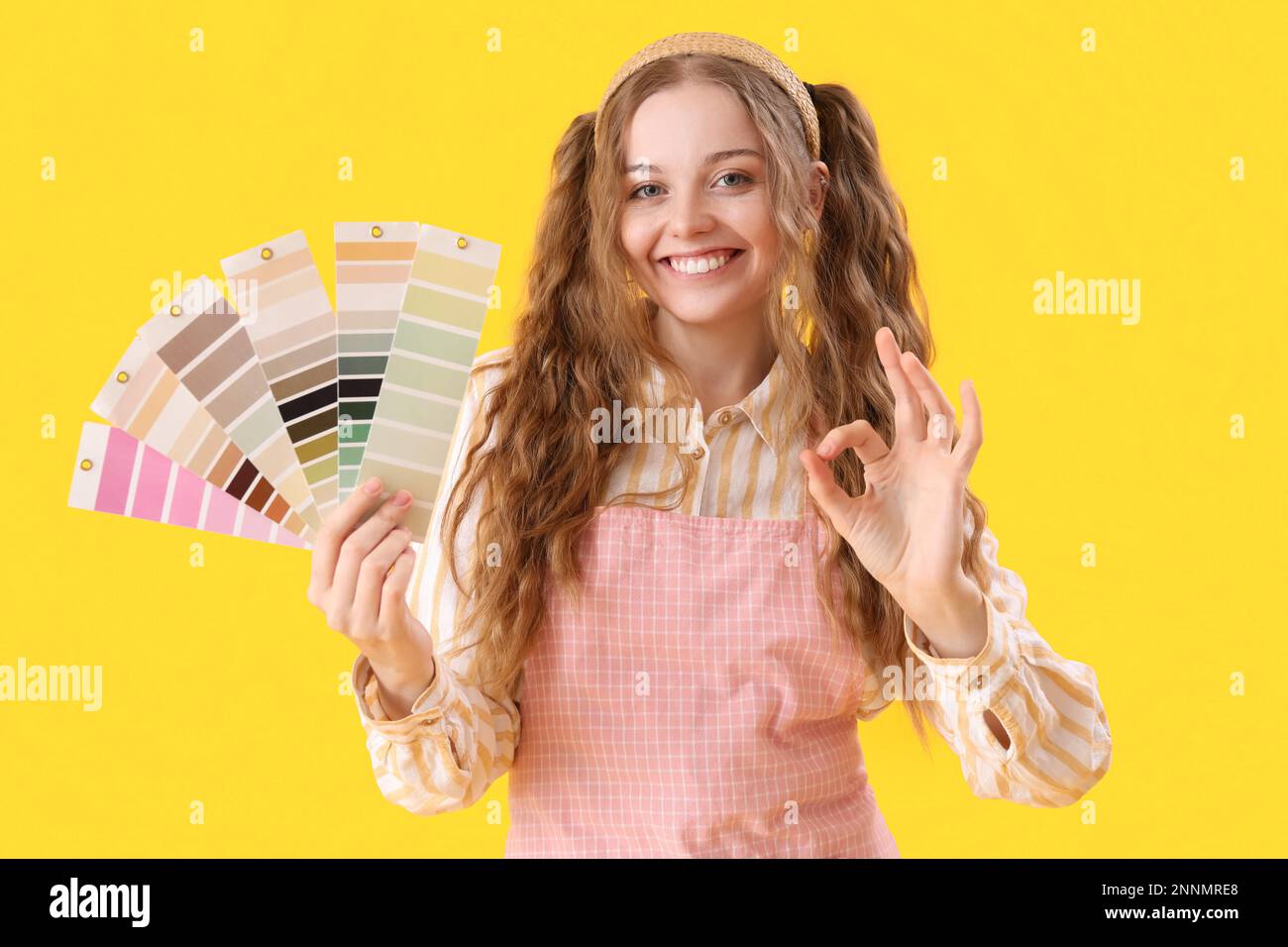 Female artist with paint color palettes showing OK on yellow background ...