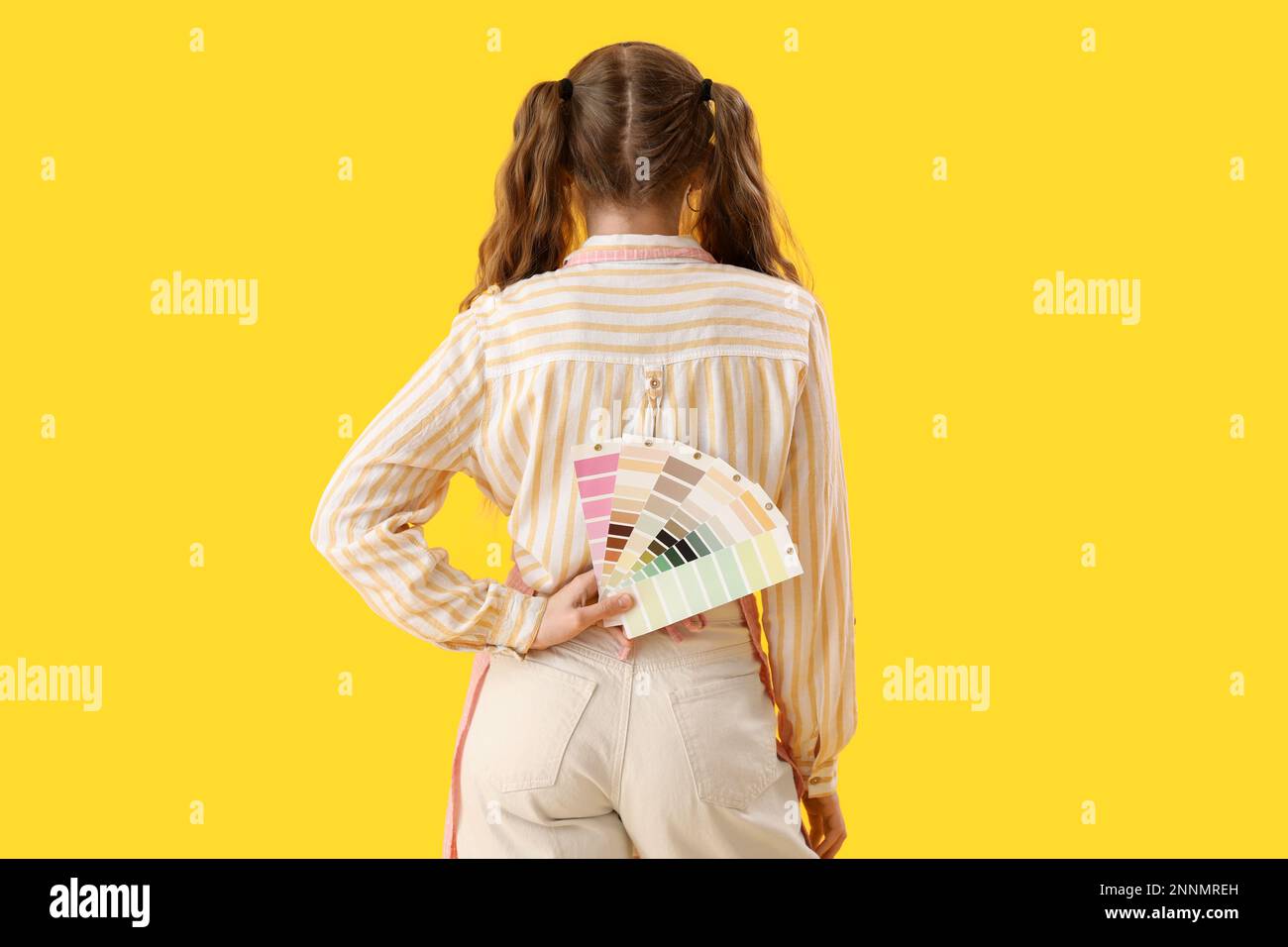 Female artist with paint color palettes on yellow background, back view ...