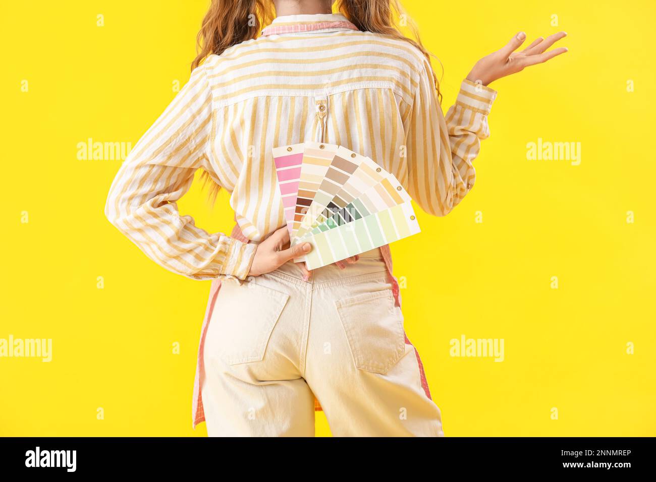 Female artist with paint color palettes on yellow background, back view ...