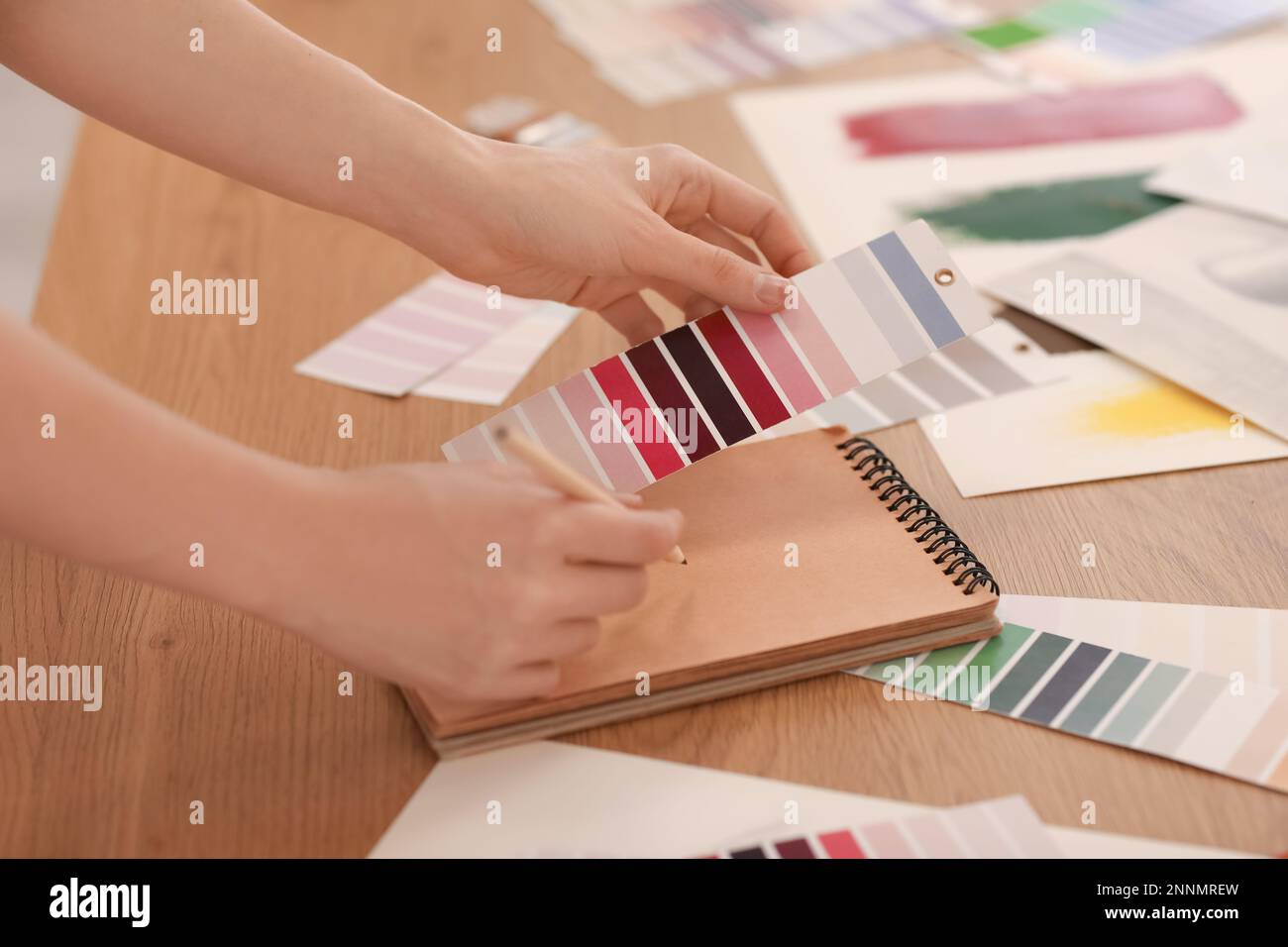 Female artist with paint color palette writing in notebook at table ...