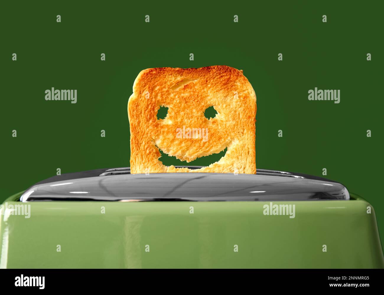 Funny slice of bread in modern toaster on green background Stock Photo ...