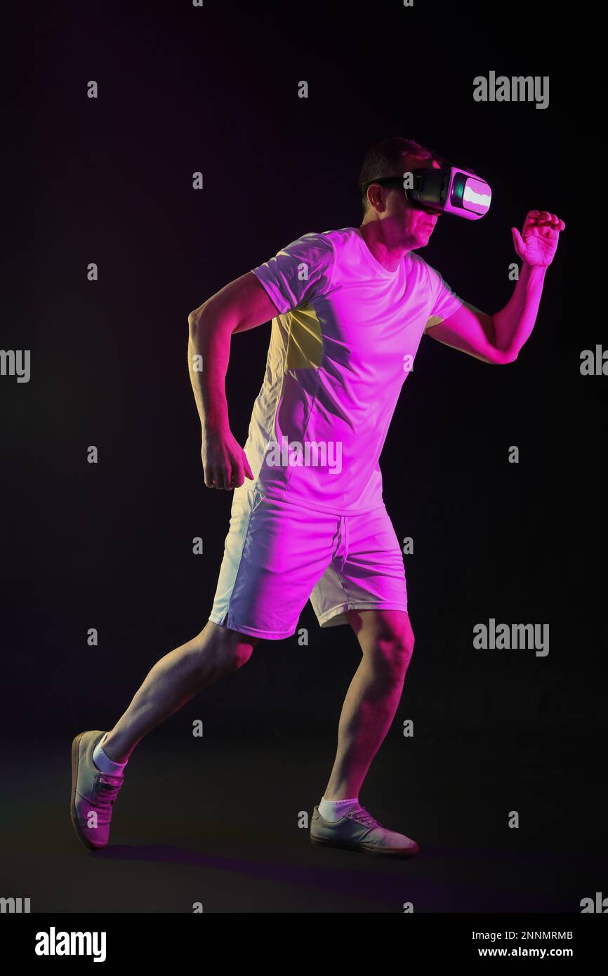 Sporty mature man in VR glasses running on dark background Stock Photo ...