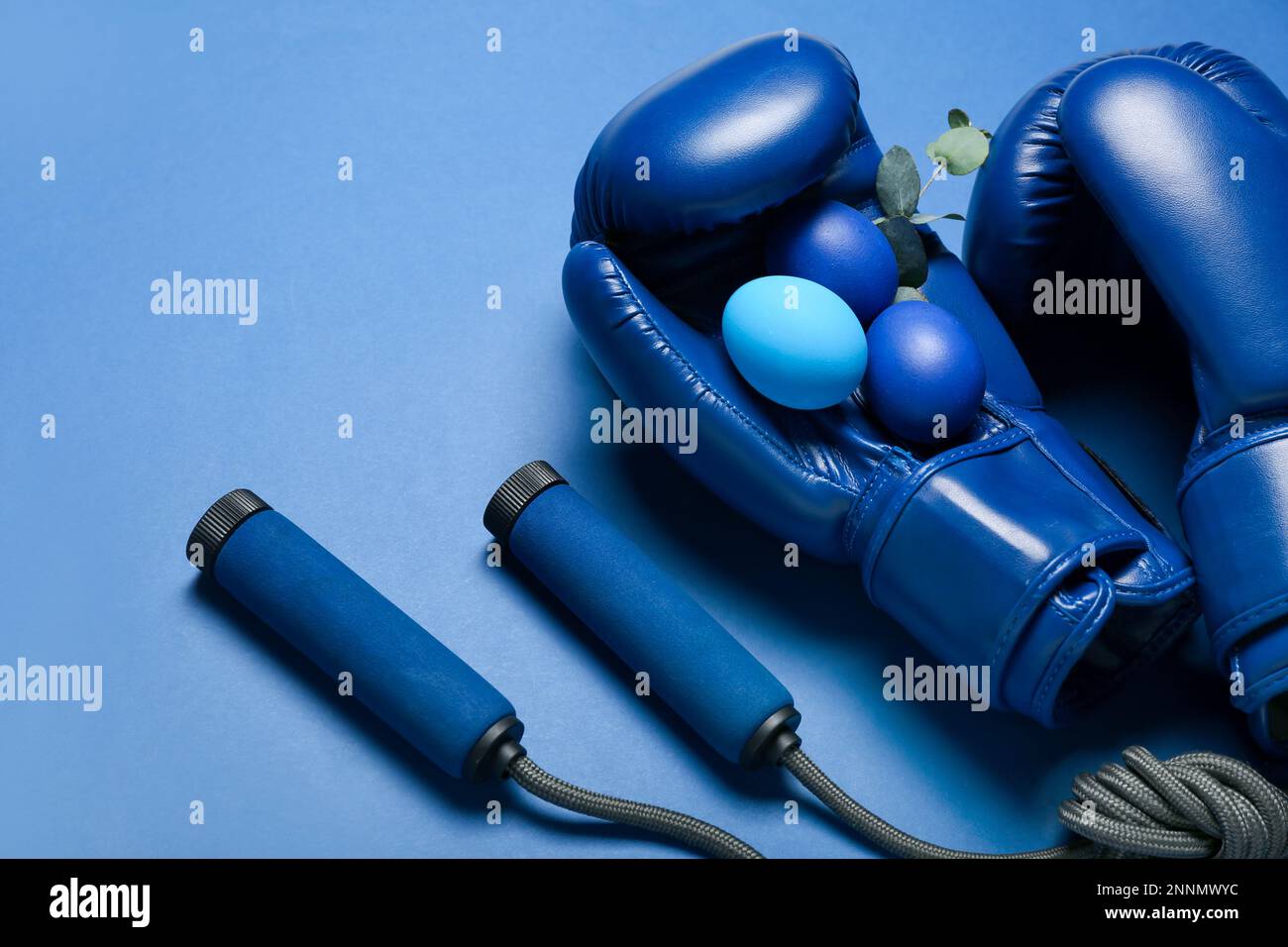 Boxing gloves with Easter eggs, eucalyptus and skipping rope on blue ...