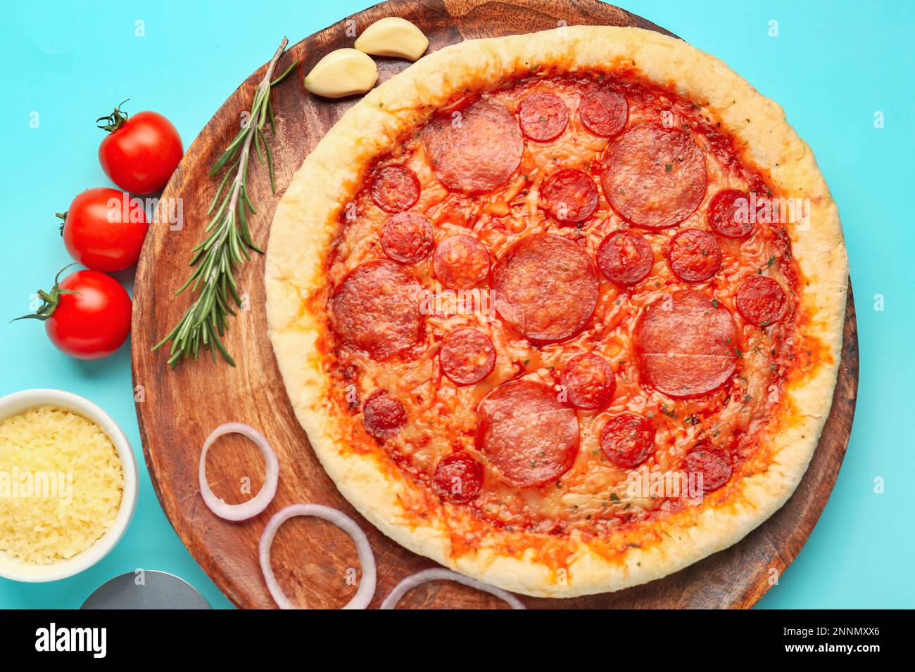 Board with delicious pepperoni pizza and ingredients on turquoise ...