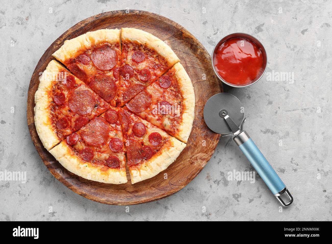 Board with delicious pepperoni pizza and cutter on grey grunge ...