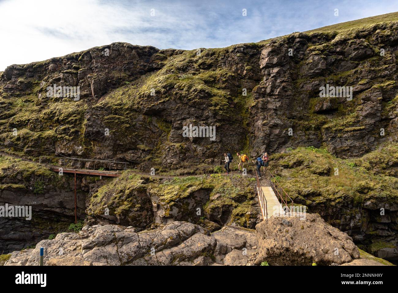 Hikers exploring beautiful Icelandic landscape. Crossing simple bridge ...
