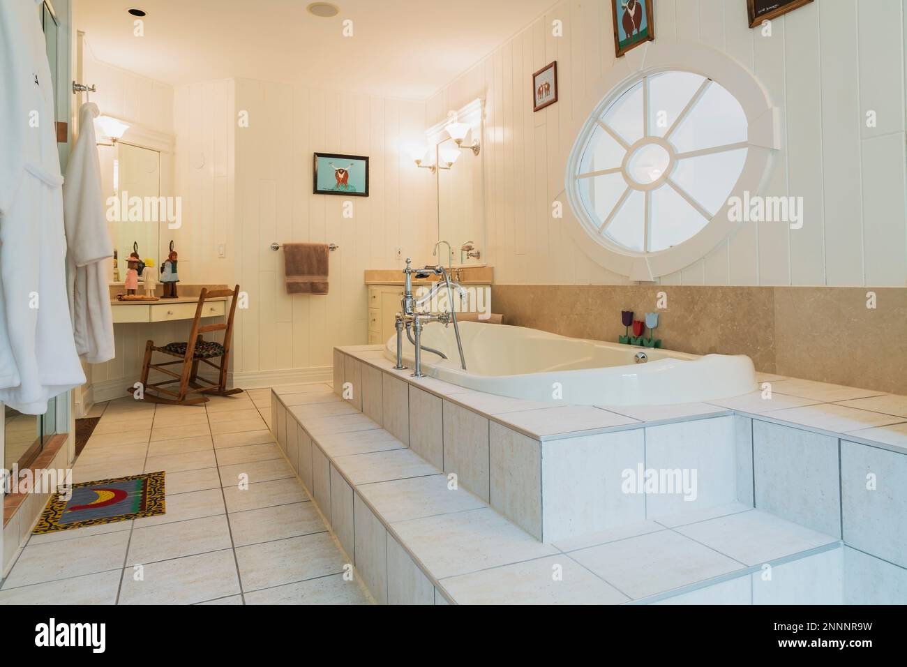 Elevated Jacuzzi bathtub encased in white ceramic base in en suite with ...