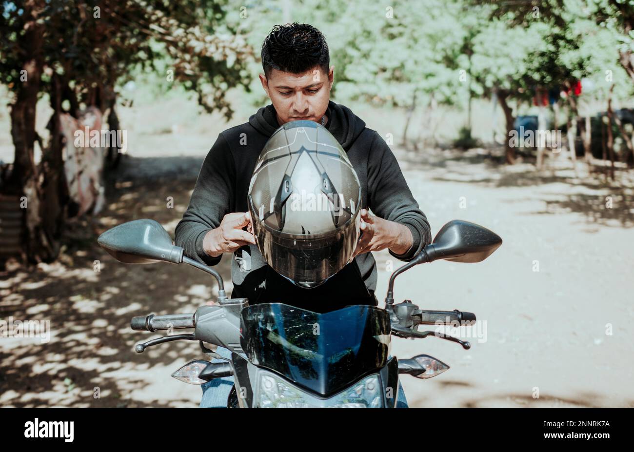 Man on motorcycle putting on helmet. Motorcyclist putting on safety ...