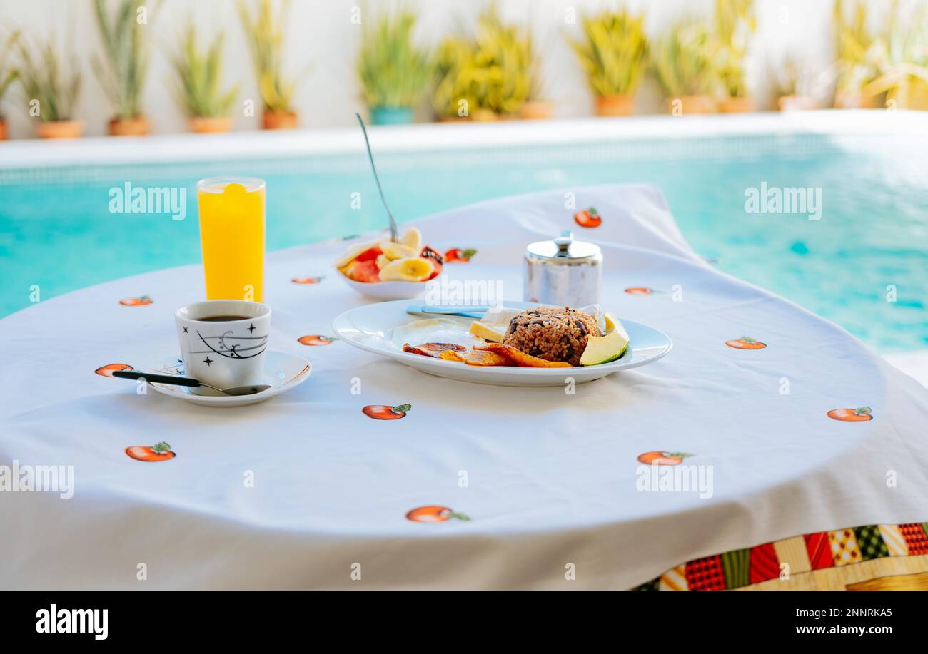 Breakfast served on the table with a swimming pool in the background ...