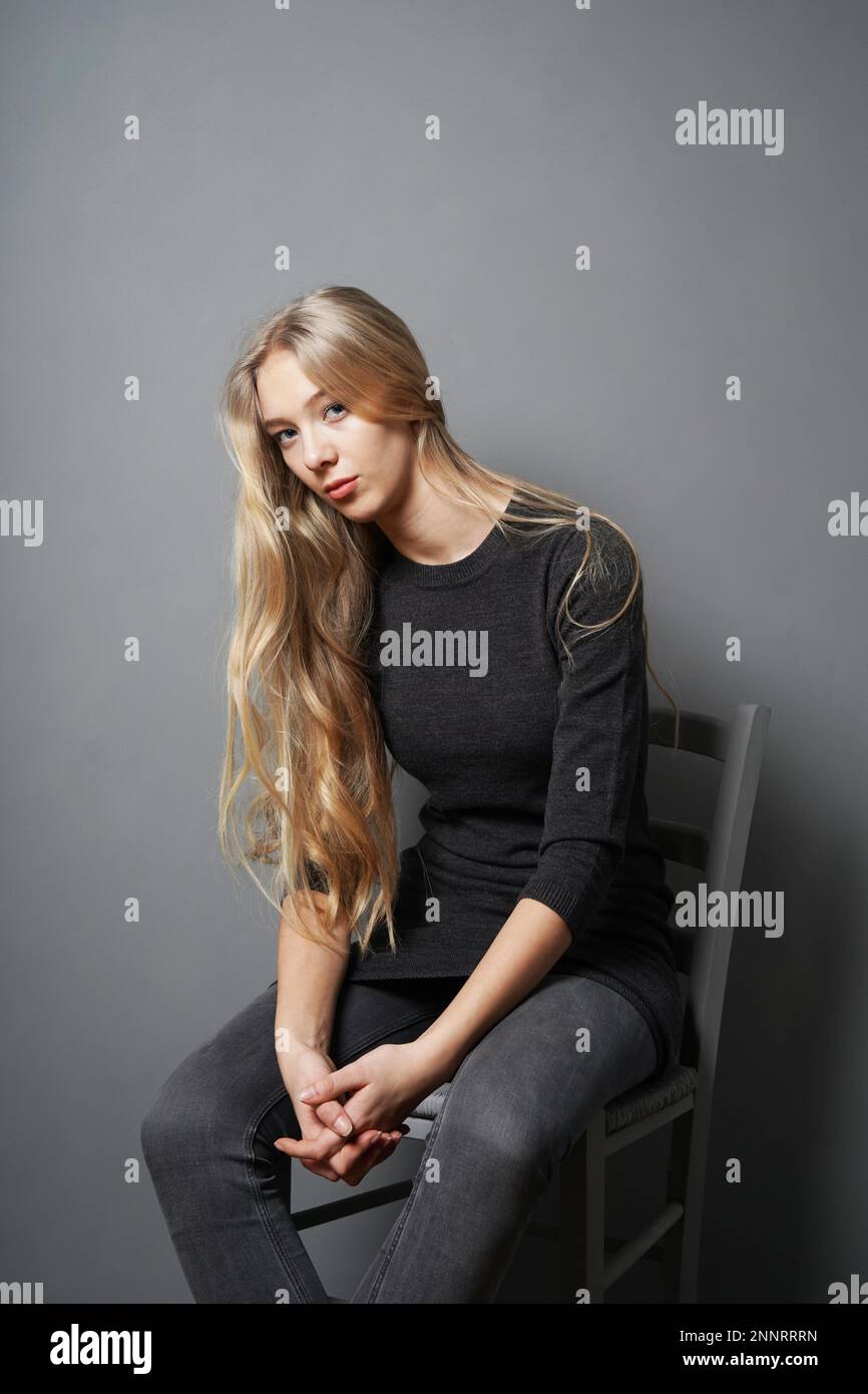 teenage girl slouching on chair - gray background with copy space Stock ...
