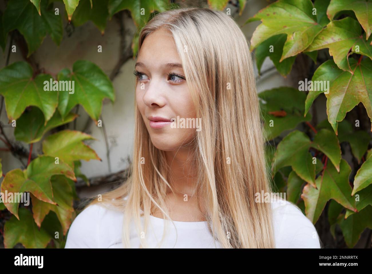 cool young woman standing outside in front of ivy clad wall - portrait ...