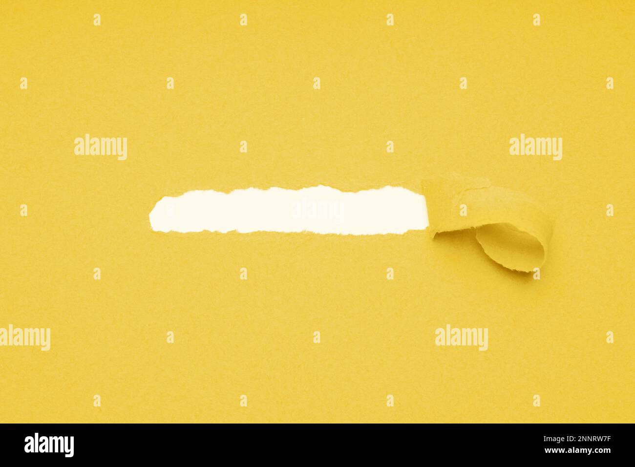 hole ripped in yellow paper background to reveal hidden copy space ...