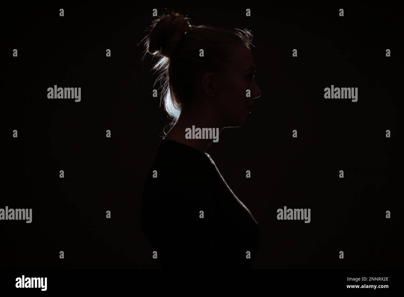 profle view of woman hiding in the dark to preserve anonymity - backlit ...