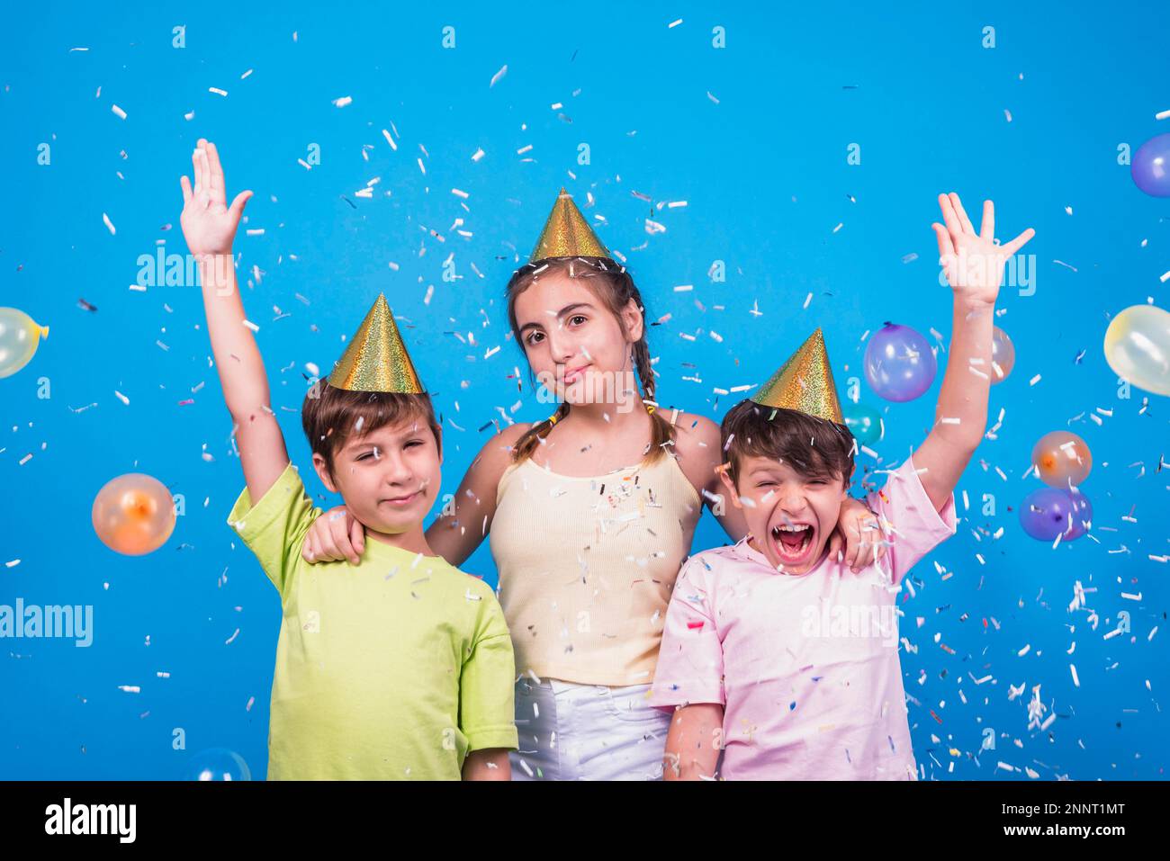 close up cheerful siblings with confetti balloons blue backdrop. High ...