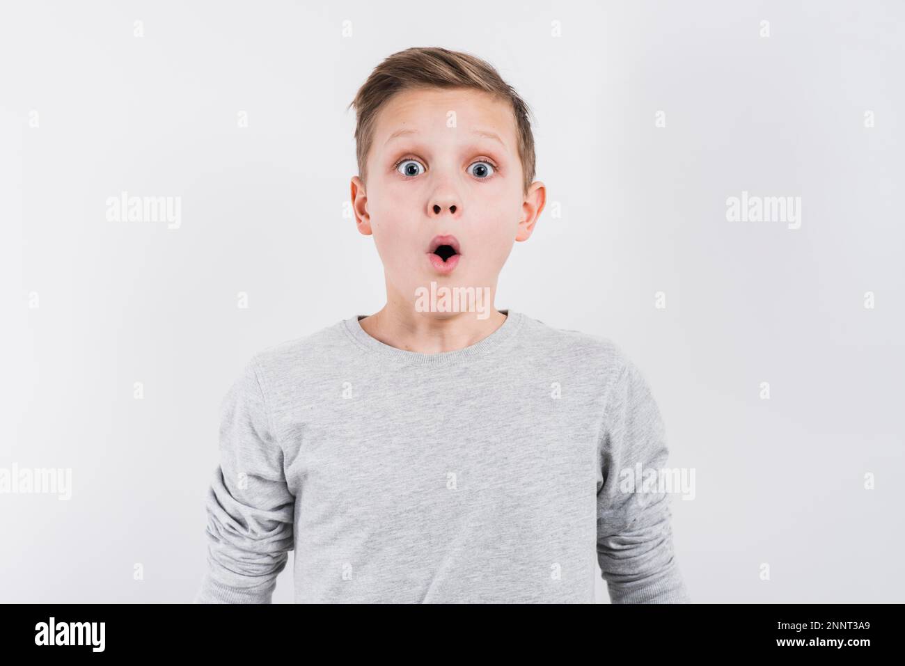 Shocked boy looking camera against gray background Stock Photo - Alamy