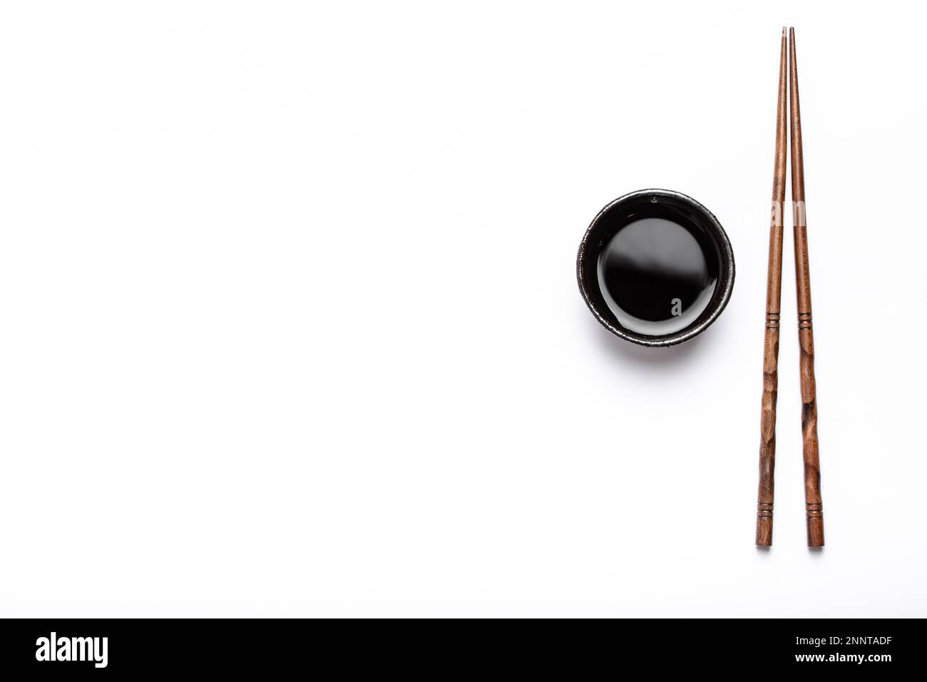 Little rustic bowl with soy sauce and wooden chopsticks over white ...