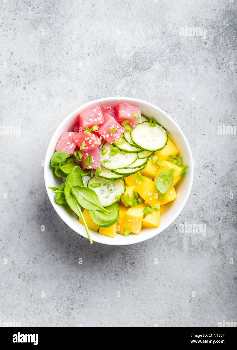 Top view of poke bowl with fresh raw tuna, mango, rice, spinach ...