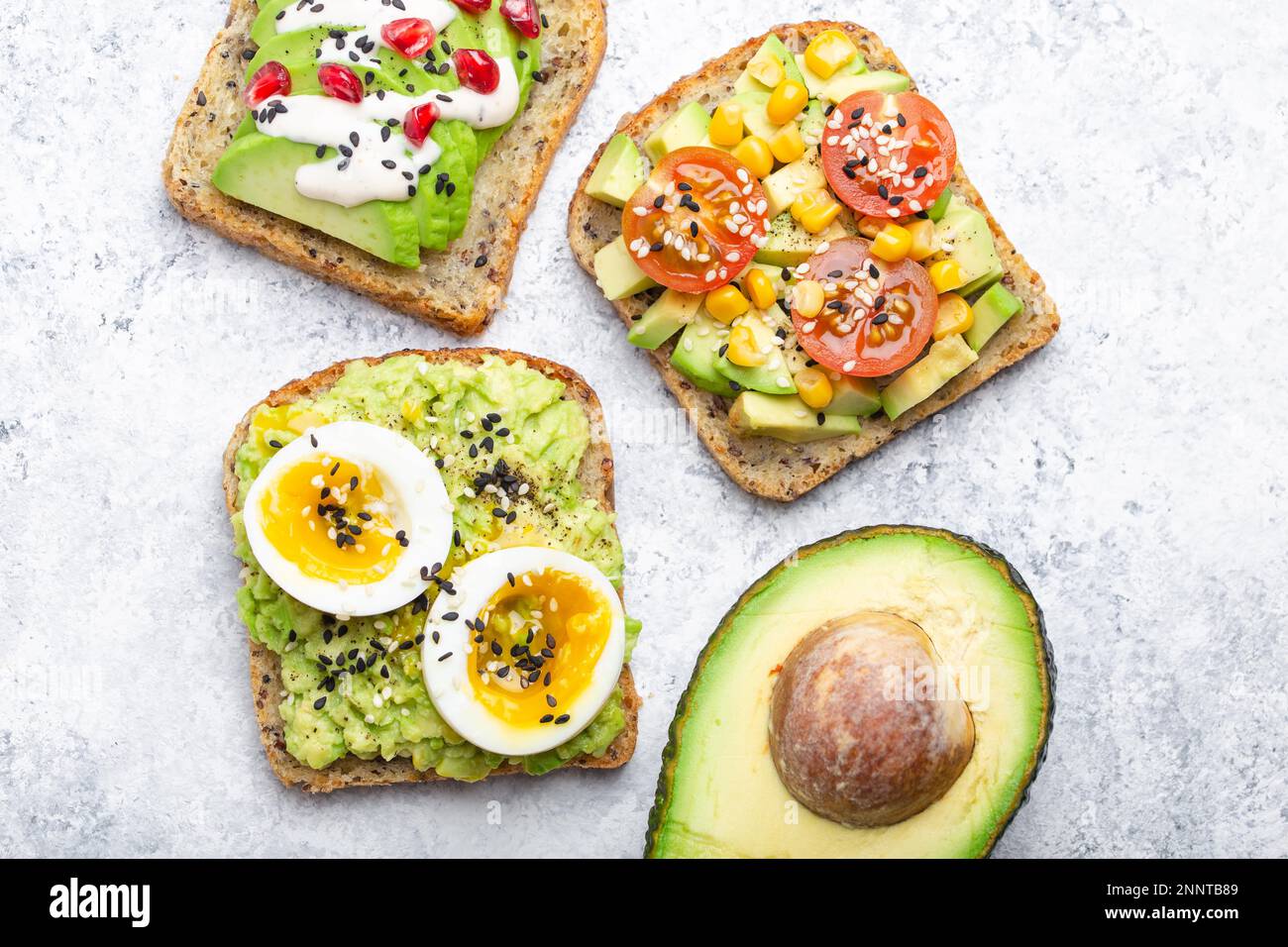Avocado toasts with egg, tomatoes, seasonings and a half of whole ...