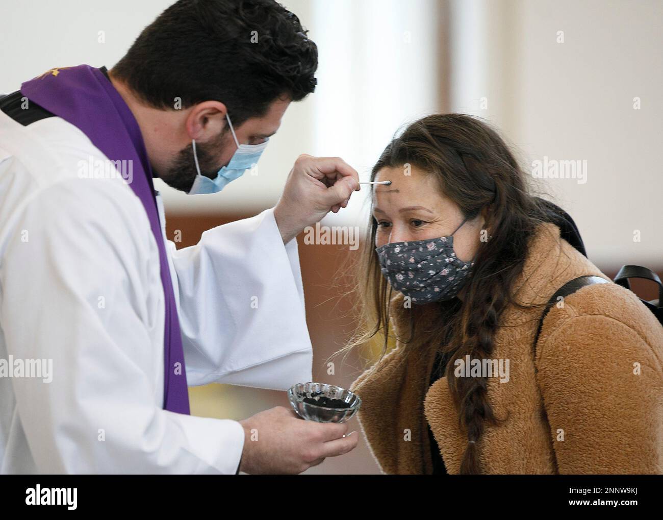 Rev. Anthony Federico makes a cross with a cotton swab while ...