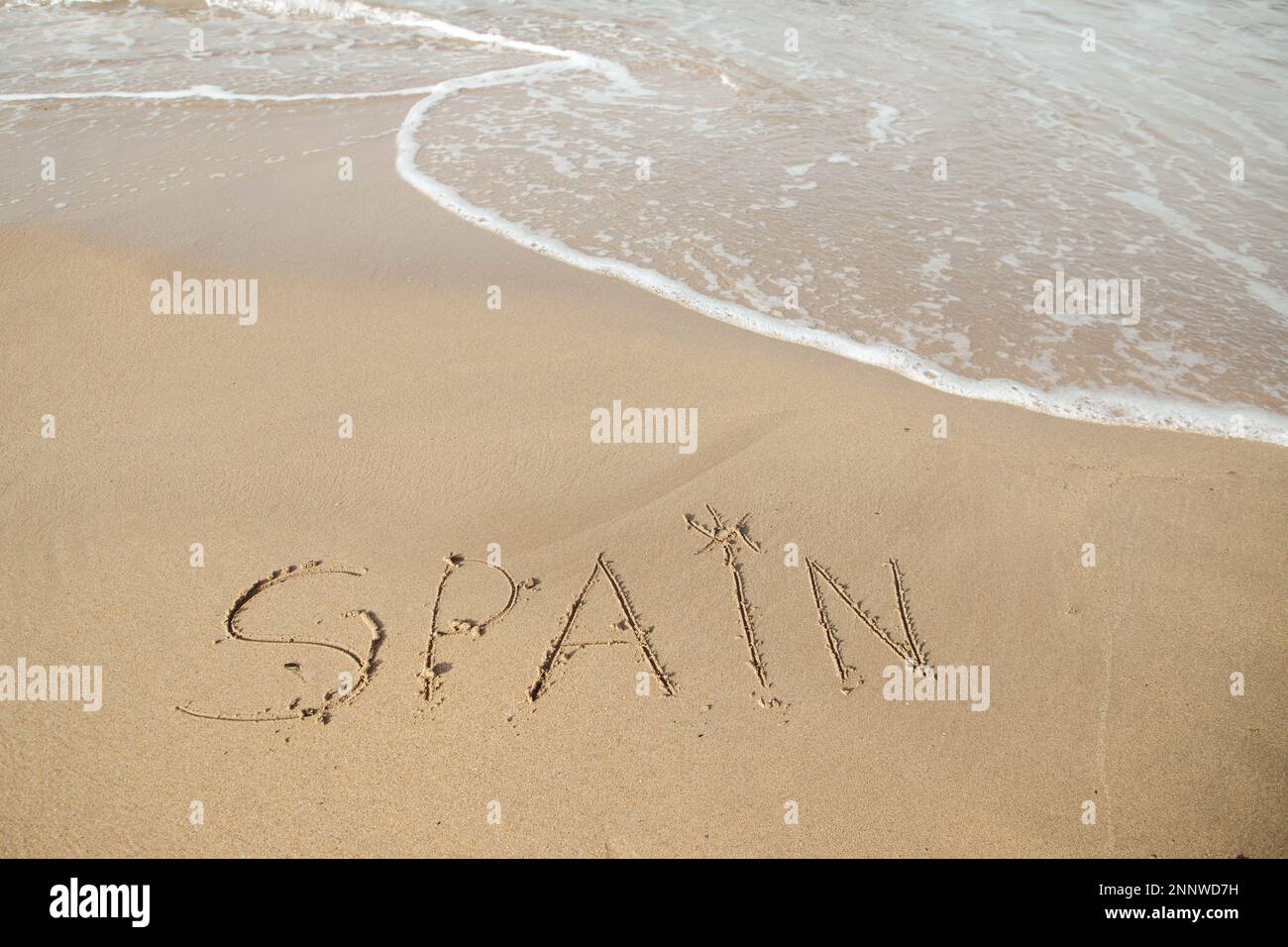 Spain lettering on the beach with wave and clear blue sea Stock Photo ...