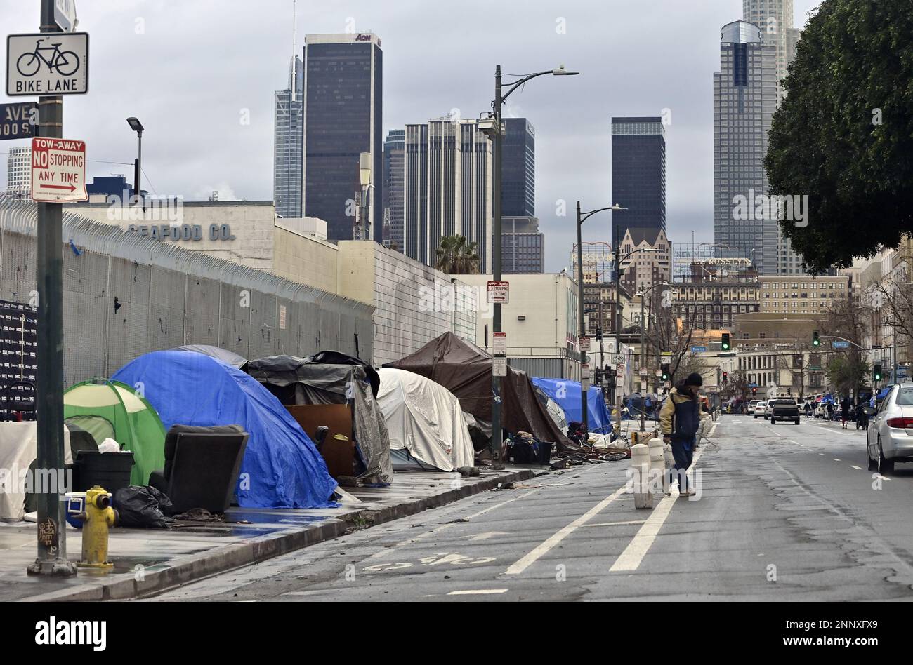 A homeless man walks across the street during a rain break in the Skid ...