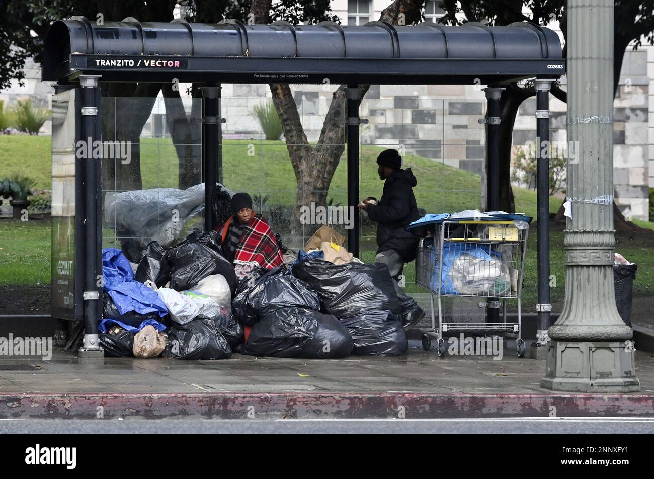A homeless woman hunkers down in a bus shelter in front of City Hall ...