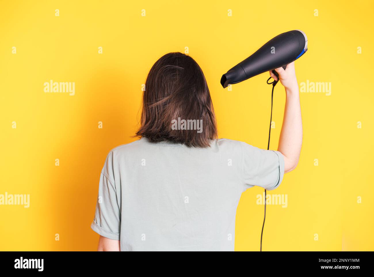 Lady drying her hair against yellow background Stock Photo - Alamy