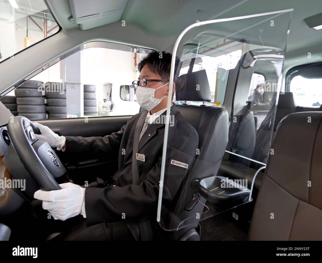 Workers install a transparent resin shield at a driver's seat in order ...