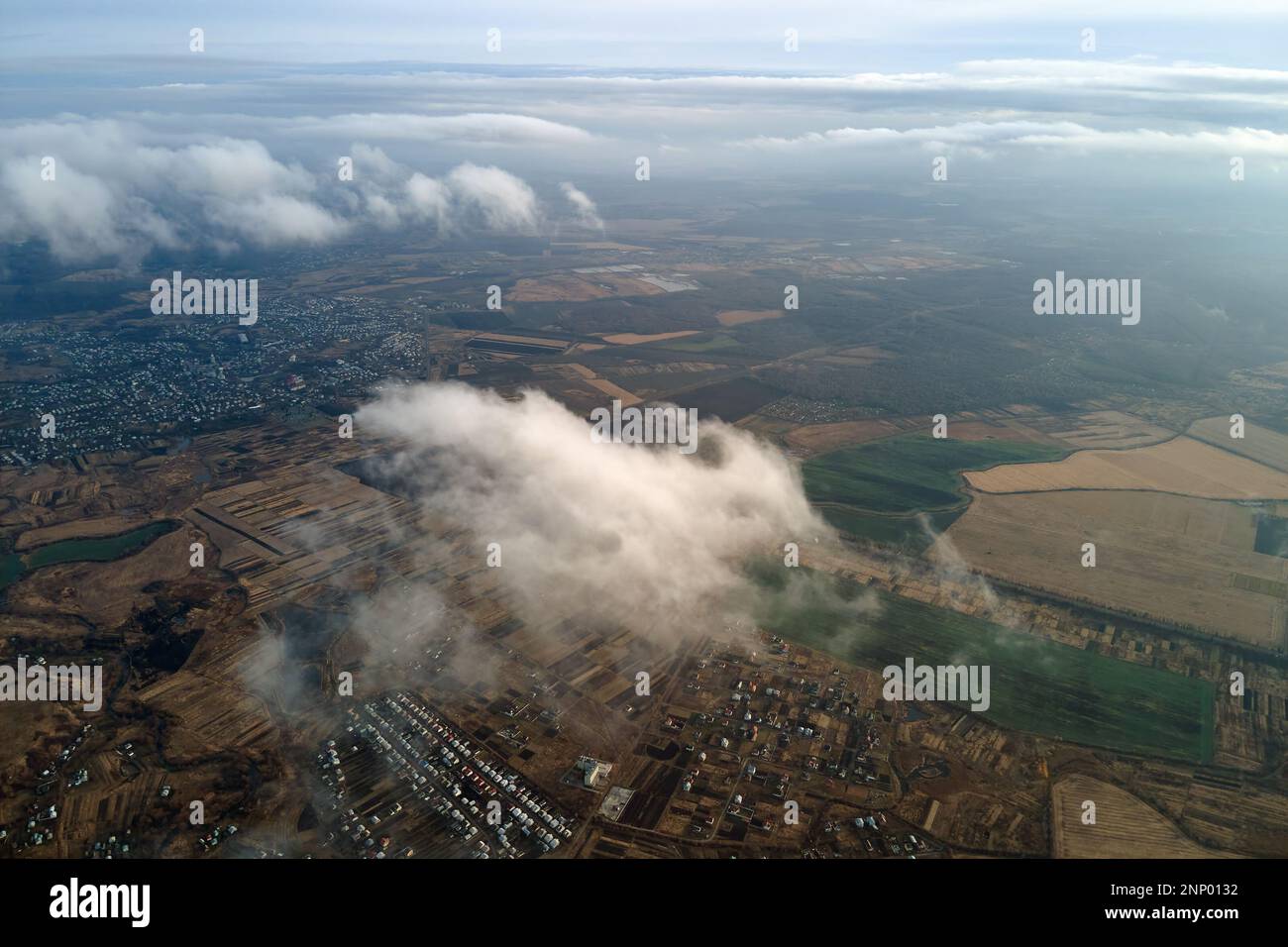 Aerial view from high altitude of distant city covered with puffy ...