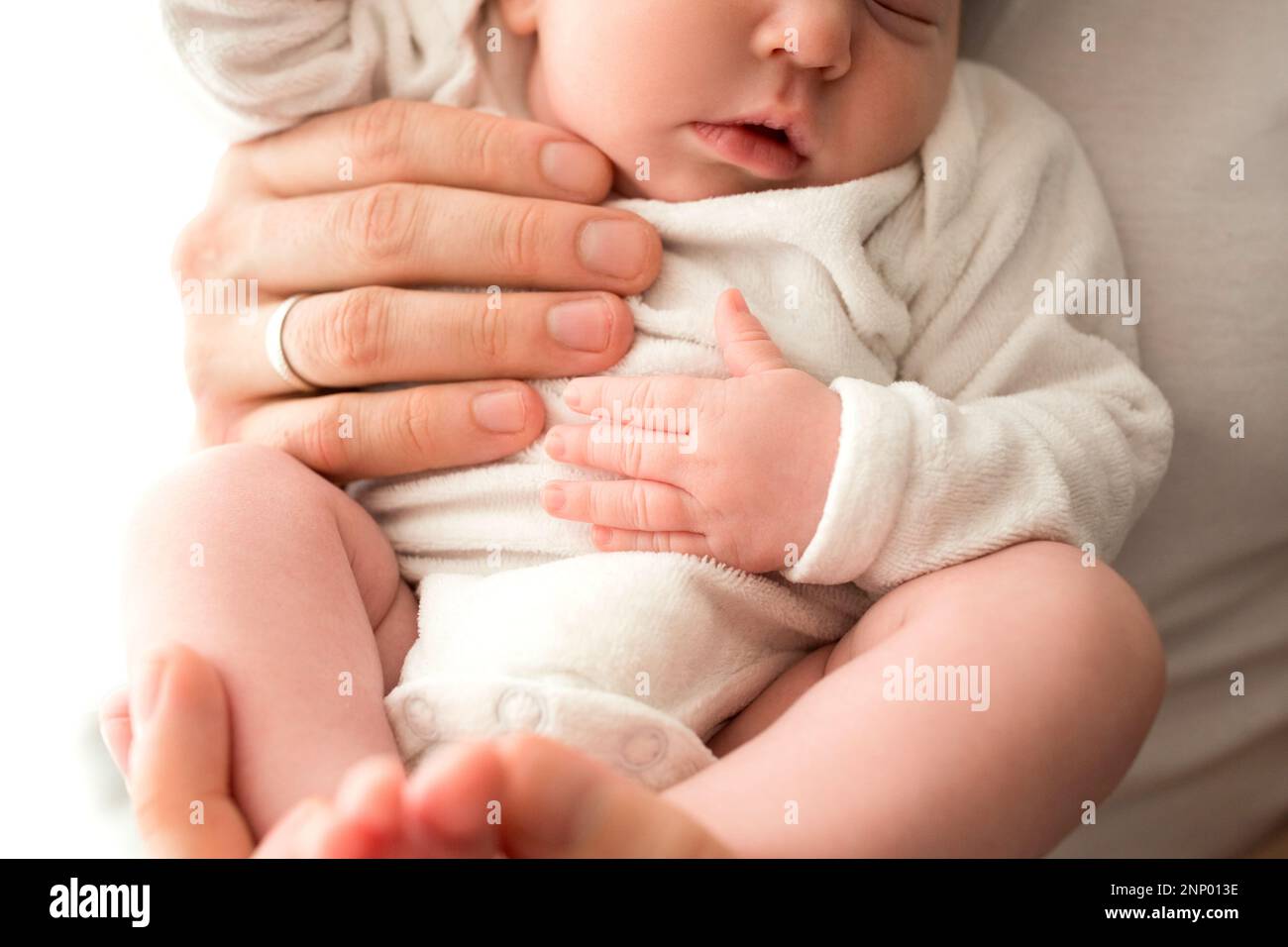 Top view of a newborn girl lying in a white overalls in the arms of her parents Stock Photo - Alamy