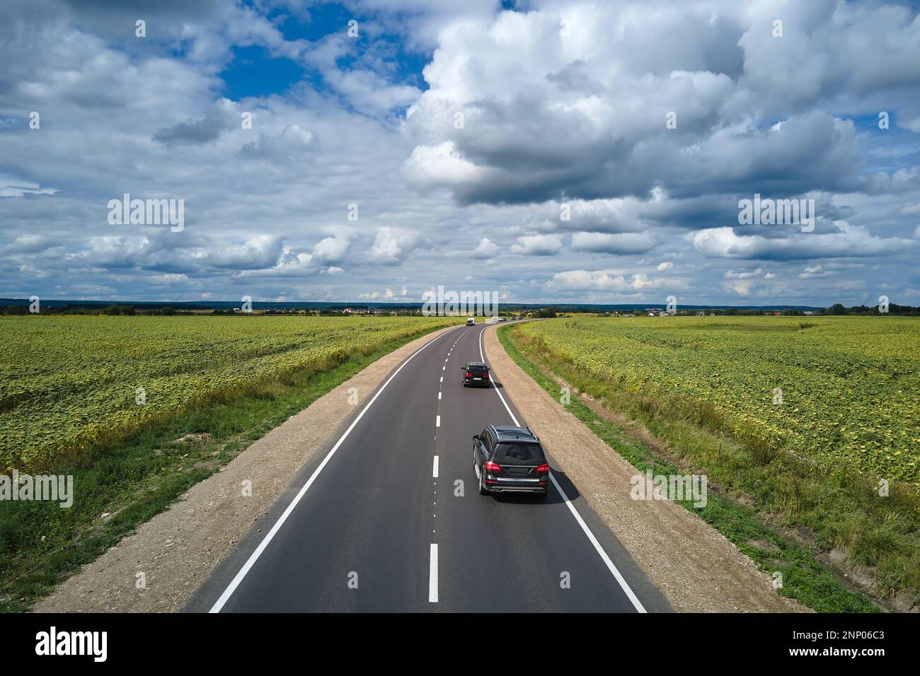 Aerial view of intercity road between green agricultural fields with ...