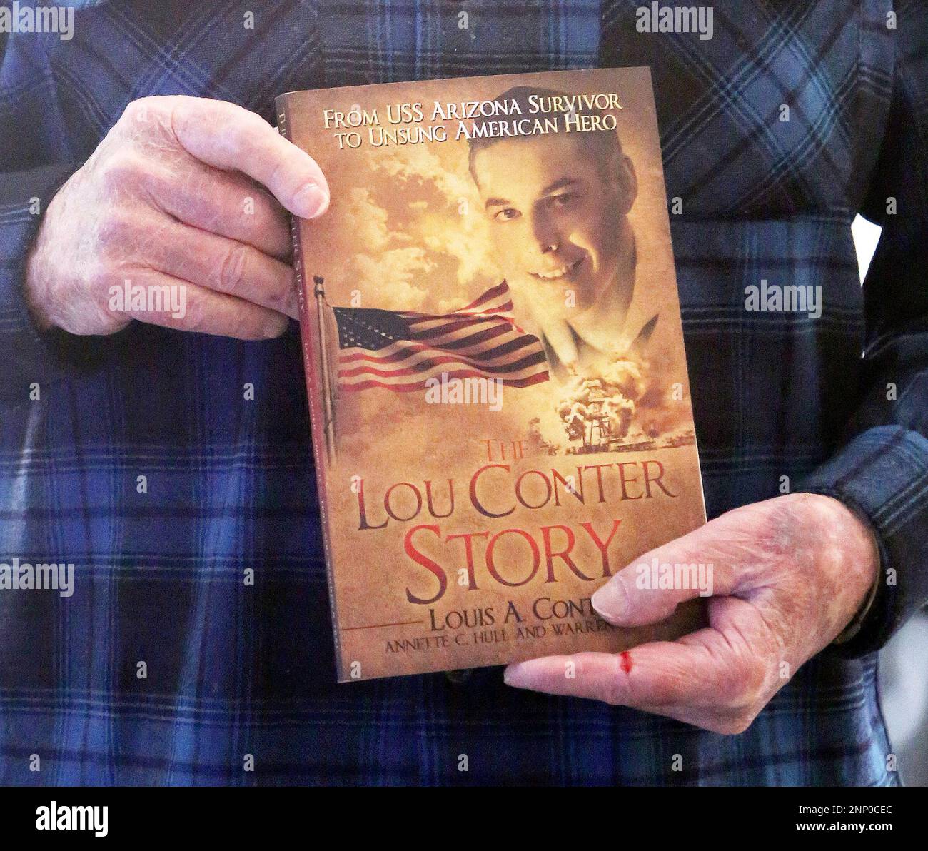 Retired Lt. Cmdr. Louis A. Conter, now 99 years old, holds a copy of ...