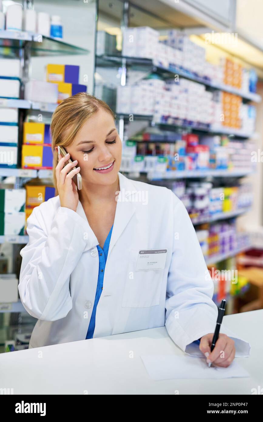 Confirming the dosage with a doctor. a young pharmacist talking on a ...