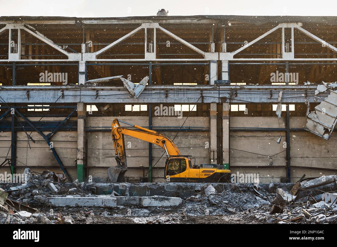 Demolition of an industrial building. An excavator with a bucket is ...
