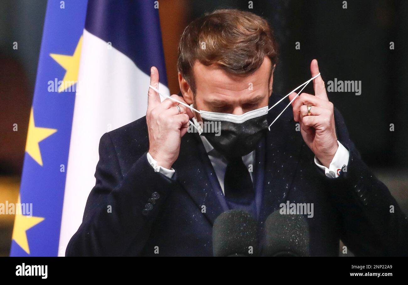 French President Emmanuel Macron takes off his face mask as he arrives ...
